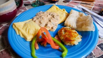Prato com omelete, creme de cogumelos, batata frita e pimentões.