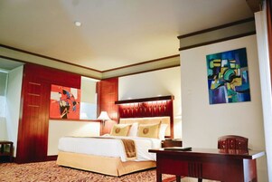 Quarto de hotel com uma cama grande, uma escrivaninha e um quadro na parede.