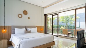 Quarto moderno com uma cama grande, televisão e varanda com mobiliário de exterior.