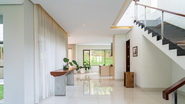 Um interior moderno com uma escada, um corredor longo e vista para o exterior.