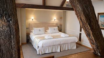 Quarto com uma cama grande, duas luminárias de cabeceira e um vigamento de madeira no teto.