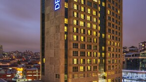 Um hotel alto com um letreiro chamativo 'DEDEMAN', vários andares e um design arquitetônico moderno.