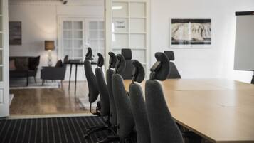 Uma sala de conferências com uma mesa comprida e fileiras de cadeiras.