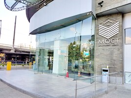 Um edifício moderno com fachada de vidro, guarda-corpo de metal e uma placa com a inscrição