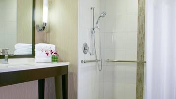Casa de banho moderna com chuveiro, lavatório com espelho e porta-toalhas.