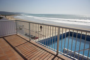 Uma varanda com vista para a praia e uma piscina.