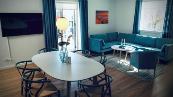 Uma sala de estar moderna com uma mesa de jantar branca, sofá verde-turquesa e cadeiras.