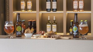 Uma área de bar com prateleiras de garrafas e copos, uma cesta de pão e uma garrafa de cerveja.