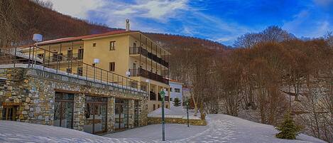 Um hotel com fachada de pedra, várias varandas e uma paisagem coberta de neve.