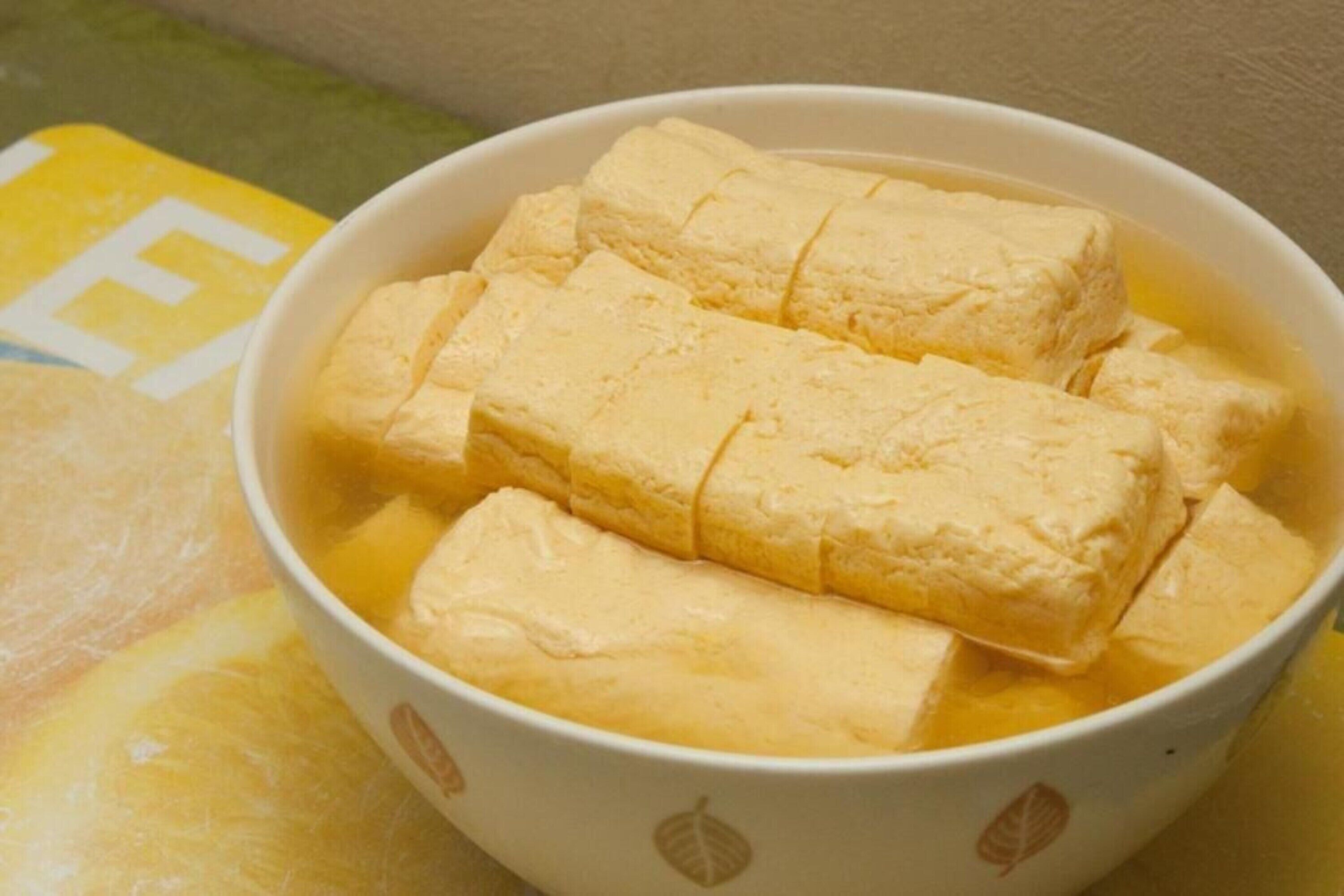 Uma tigela com cubos de tofu em líquido transparente.