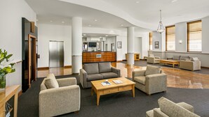 Um hall amplo com balcão de atendimento, área de estar e mesa de centro de madeira.