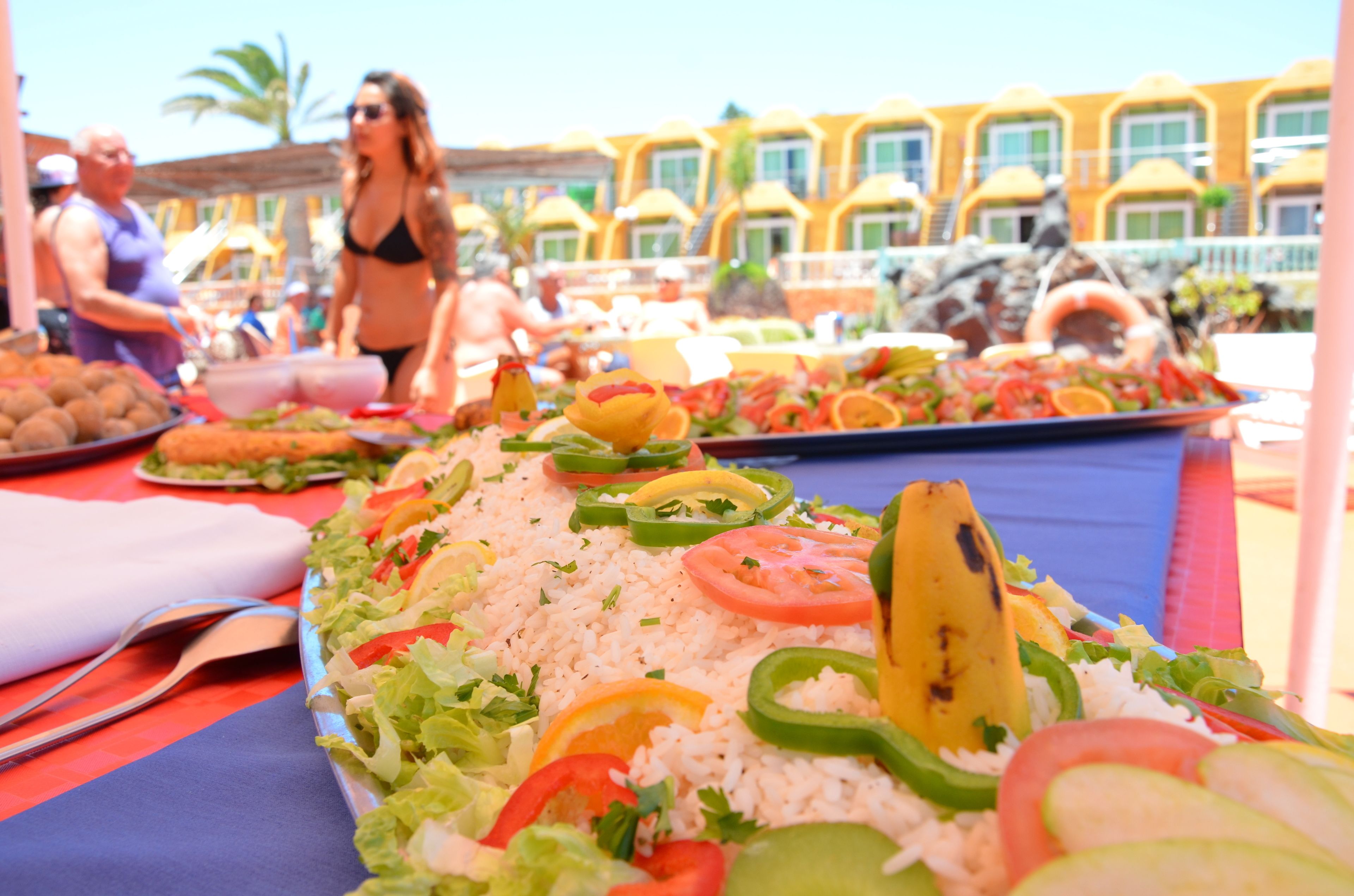 Mesa de buffet com variedade de pratos, incluindo arroz, legumes e frutas.