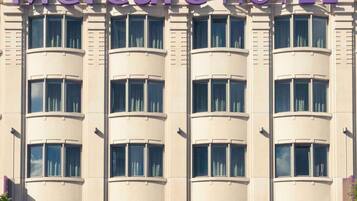 Um edifício de hotel com o nome 'Mercure Hotel' em destaque. Apresenta um estilo arquitetônico moderno, com várias varandas e janelas amplas.