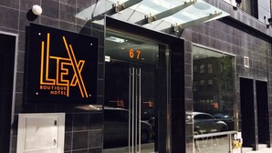 Um edifício moderno com entrada de vidro e uma placa com a inscrição "LEX BOUTIQUE HOTEL".