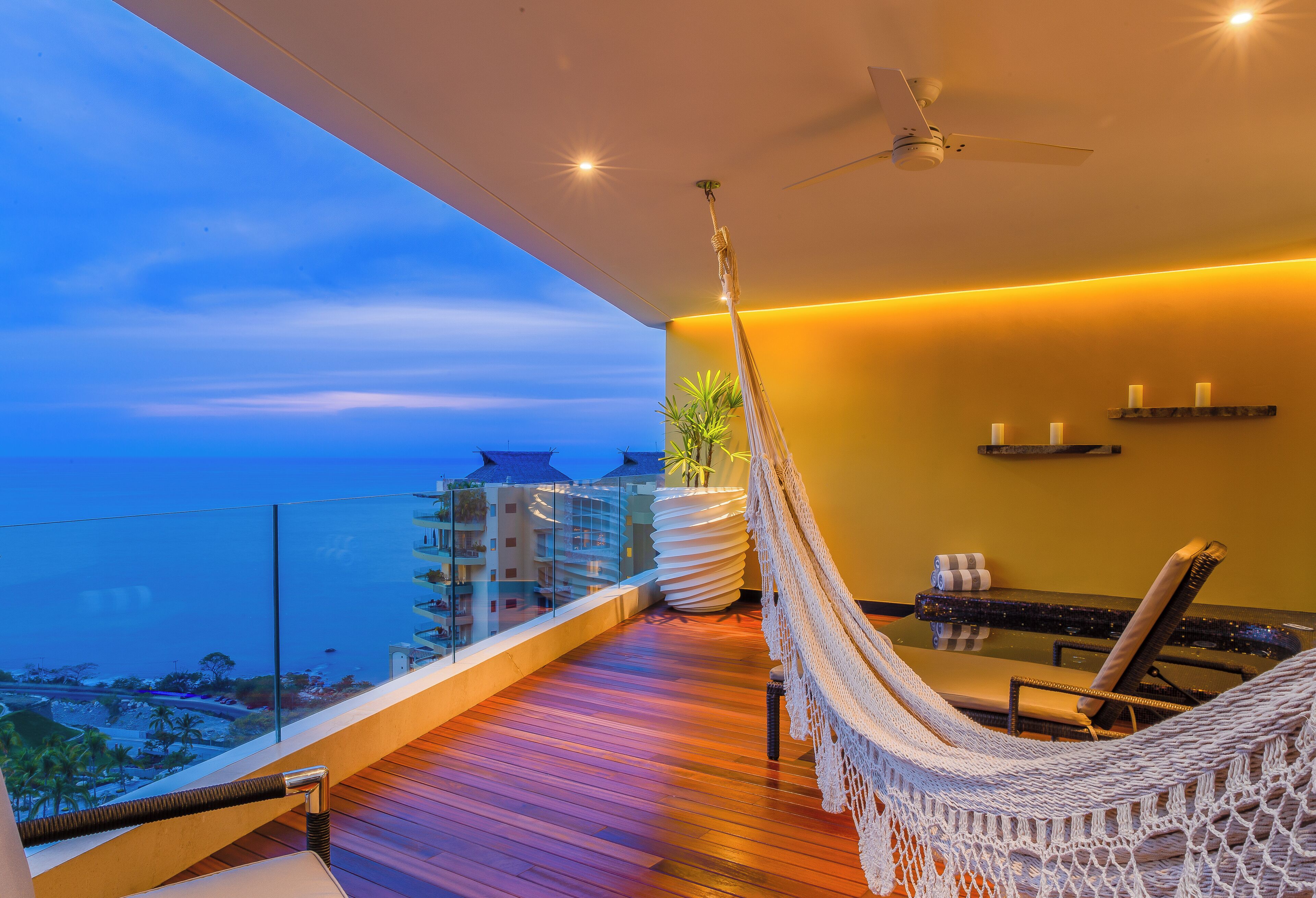 Uma varanda com rede, ventilador de teto e vista para o oceano.