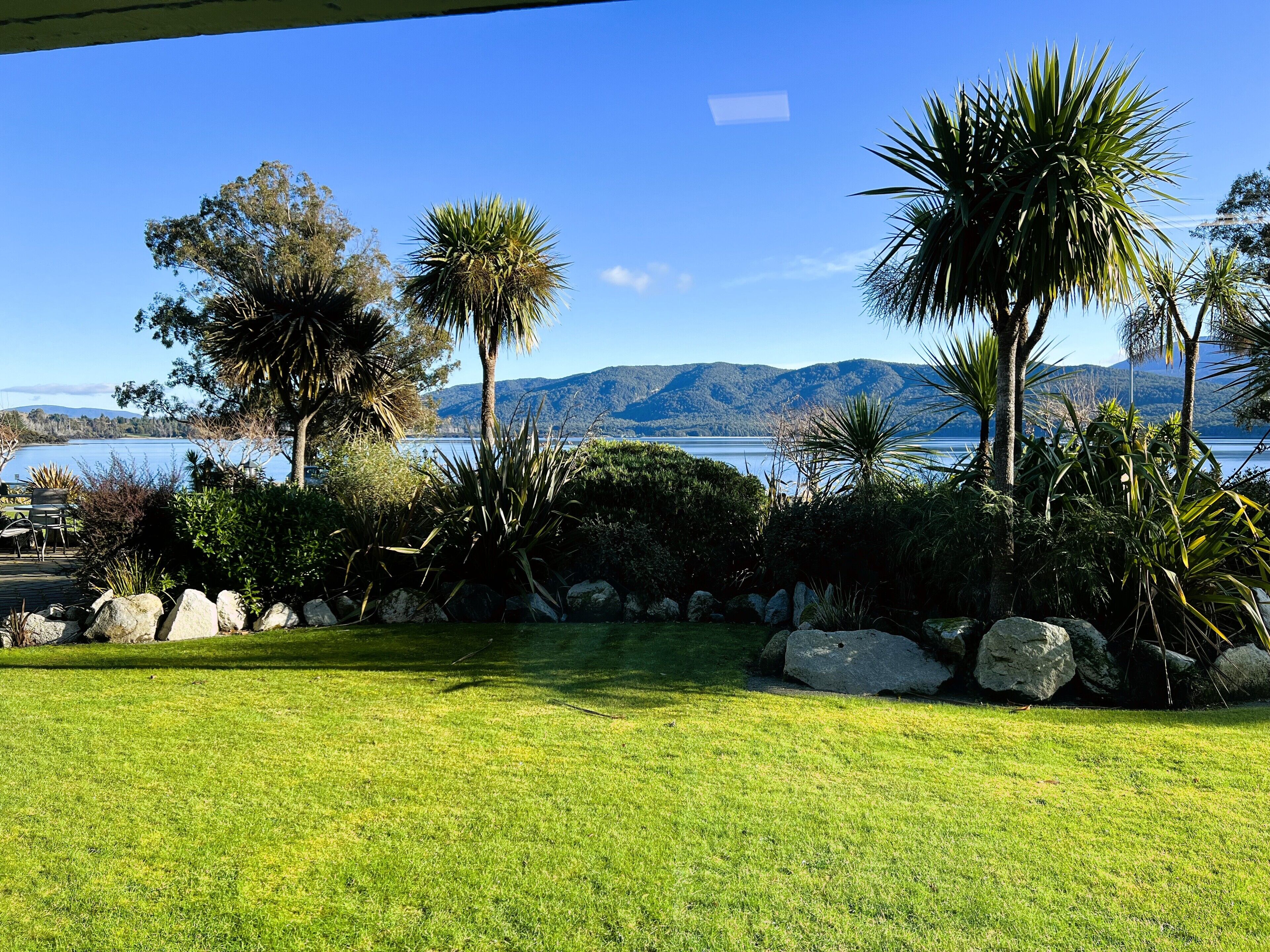 Um gramado bem cuidado com vista para um lago e montanhas ao fundo.