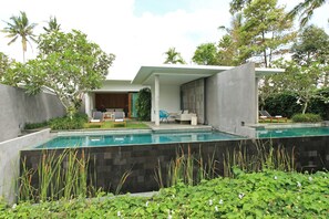 Uma área moderna à beira da piscina, com piscina integrada, espreguiçadeiras e um espaço de estar coberto.