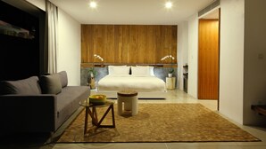 Quarto moderno com uma cama grande, um sofá, uma mesinha e uma parede de destaque em madeira.