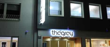 Um edifício com uma placa indicando "thegrey" e um carro estacionado na frente.
