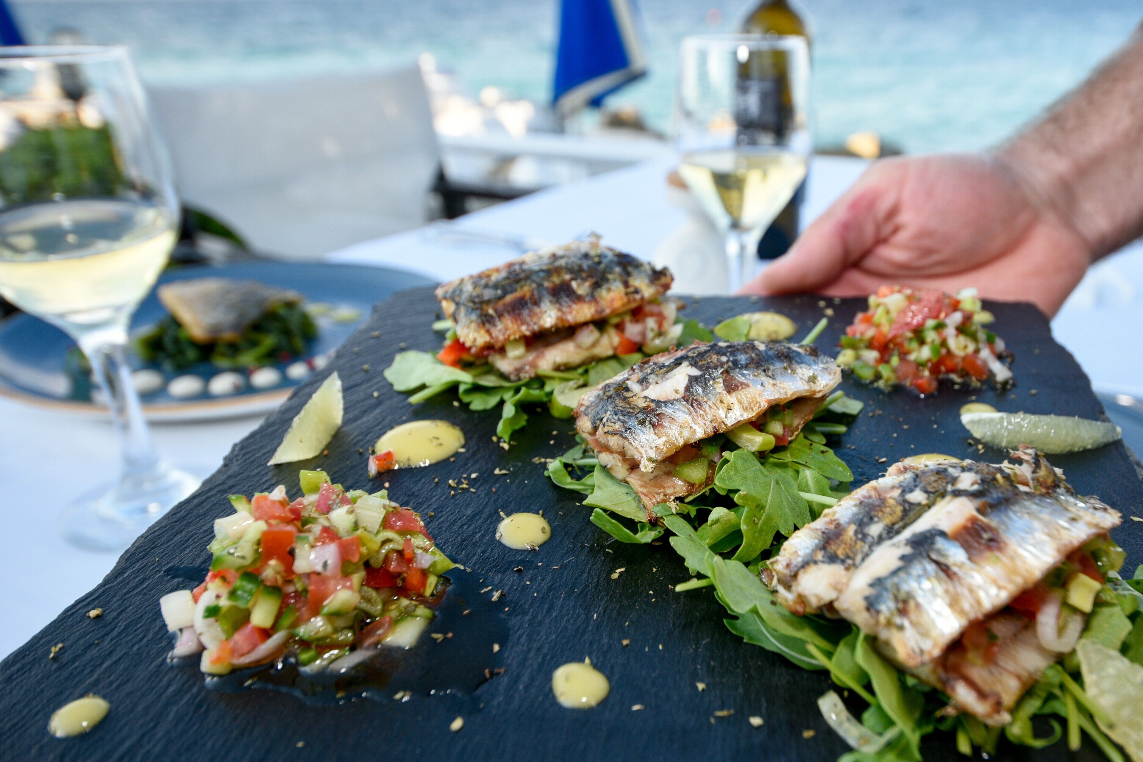 Prato de frutos do mar com peixe grelhado e salada sobre uma tábua de ardósia.