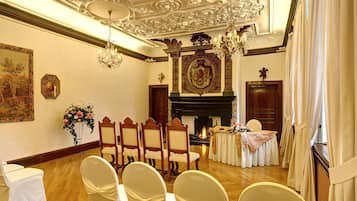Uma sala de jantar formal com teto ricamente decorado, lustres e lareira.