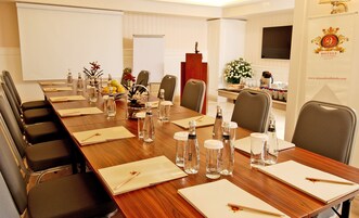 Uma sala de conferências com uma longa mesa de madeira, várias cadeiras, garrafas de água e um pódio.