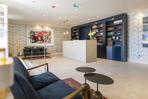 Um lobby moderno com balcão de recepção, área de estar e estante de livros.