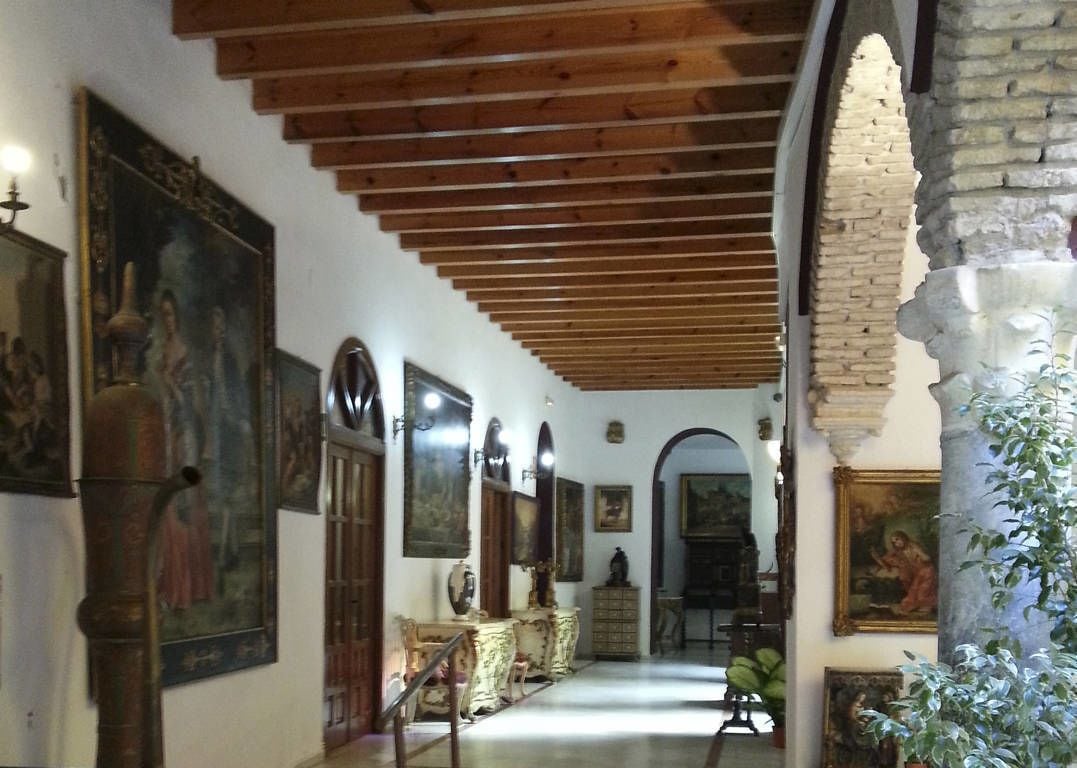 Um corredor com vigas de madeira, pinturas e um pilar de tijolo.