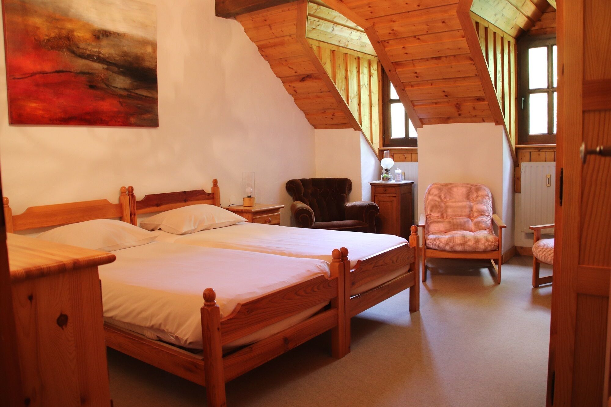 Quarto com duas camas de madeira, uma cadeira e uma escrivaninha.