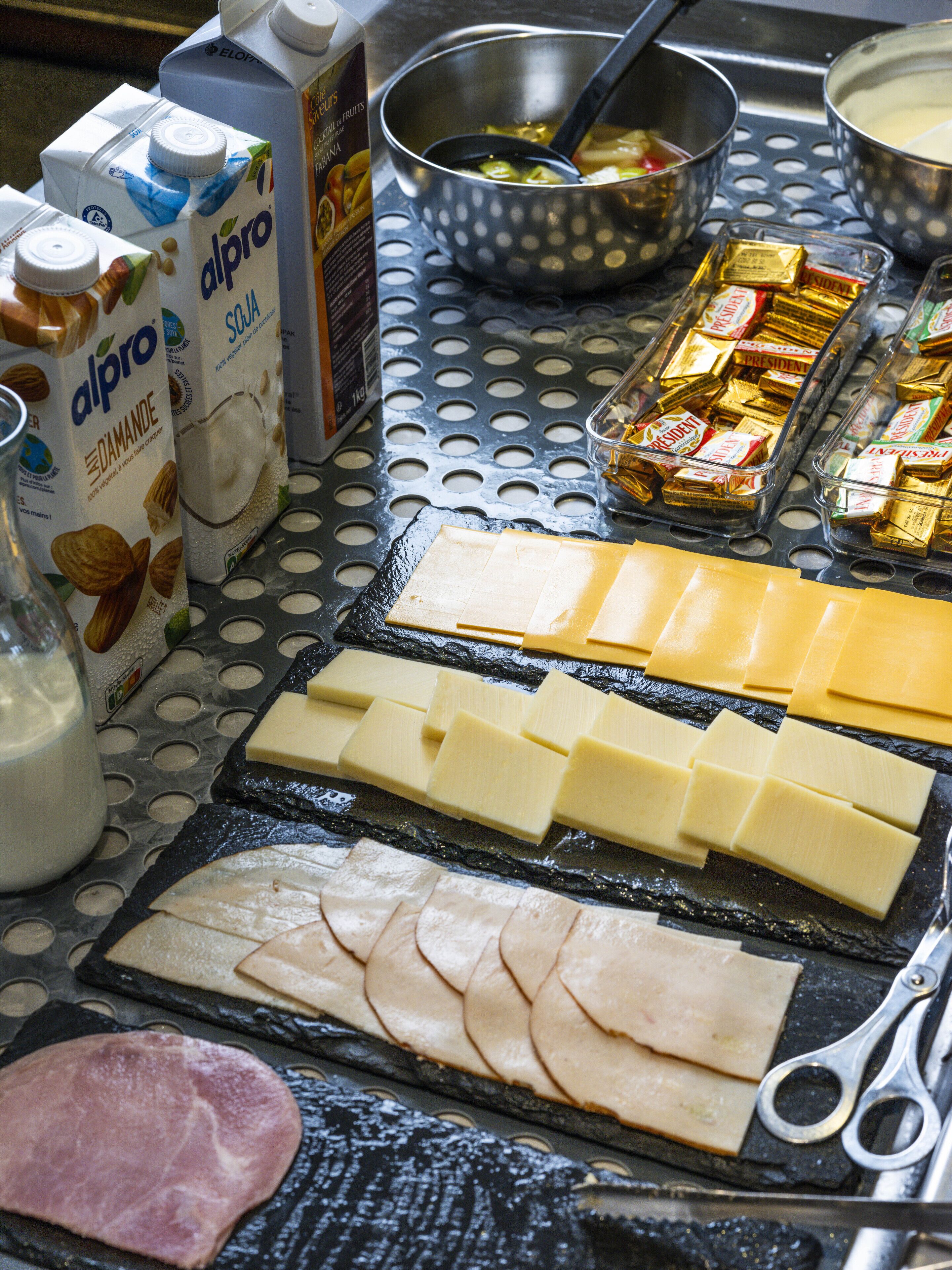 Uma mesa com diversos alimentos, incluindo queijo, presunto e caixas de leite.