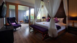Um quarto espaçoso com uma cama grande, um banco, uma cadeira e uma televisão.
