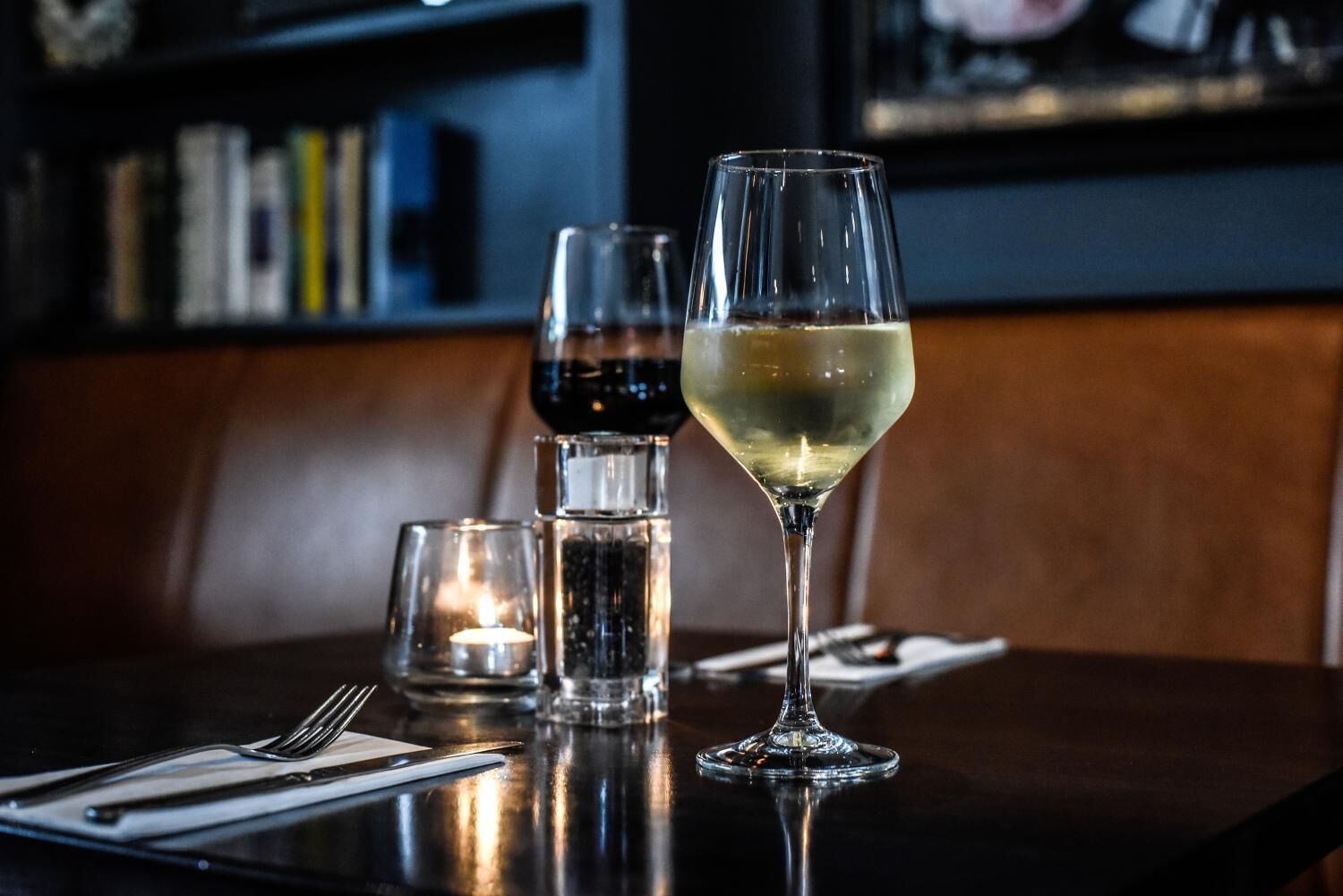 Uma mesa com uma taça de vinho, um copo de água e uma vela.