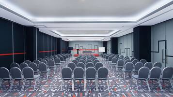 Uma sala de conferências com fileiras de cadeiras, um palco e um pódio.