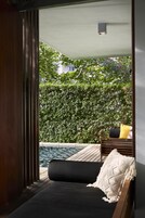 Quarto moderno com vista para uma piscina e vegetação exuberante.
