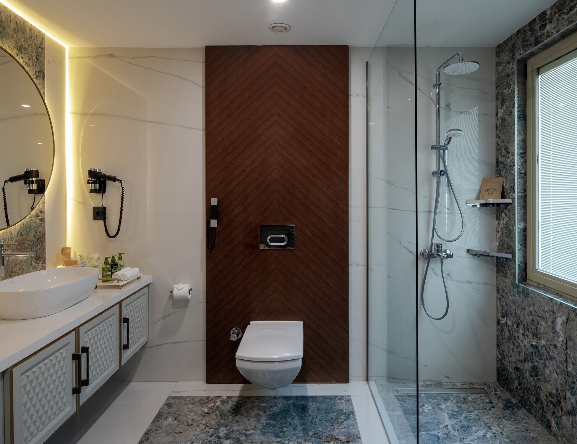 Uma casa de banho moderna com um espelho grande, uma sanita branca, uma loiça e um espaço de duche com parede de vidro.