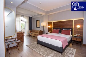 Quarto de hotel moderno com uma cama grande, mesas de cabeceira, uma escrivaninha e uma cadeira.