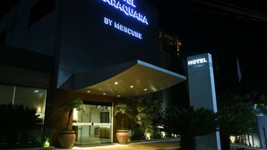 Entrada de hotel com uma grande placa iluminada que diz 'HOTEL ARANQUARA BY MERCURE'.