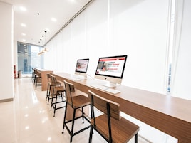 Uma sala de conferências moderna com mesas grandes, cadeiras e dois computadores Apple iMac.
