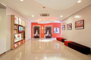 Um hall moderno com parede em vermelho, balcão de recepção e área de estar.