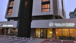 Um hotel moderno com uma seção vertical preta marcante, janelas amplas e entrada bem iluminada.