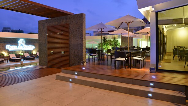 Pátio de hotel com área de estar externa, piscina e guarda-sóis.