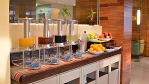 Um balcão de café da manhã com dispensadores de suco, uma saladeira e um vaso de planta.