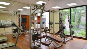 Uma academia com equipamentos de cardio, máquinas de peso e um banco.