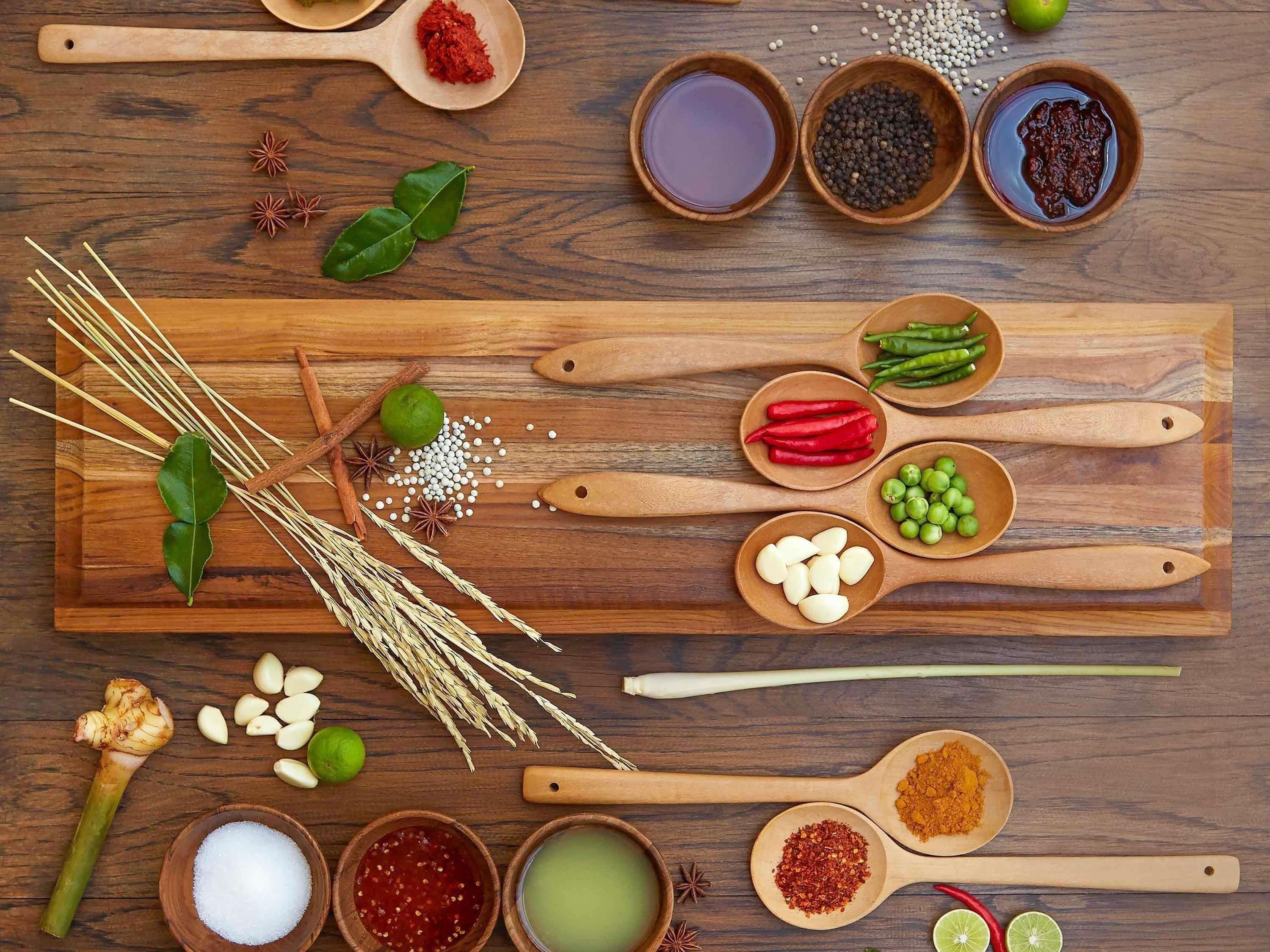 Uma tábua de corte de madeira com diversos temperos e ingredientes.