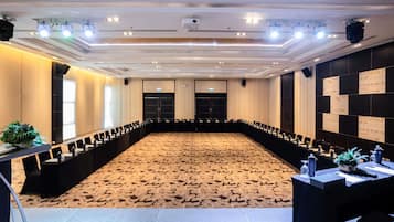 Uma sala de conferências com uma mesa comprida, cadeiras e piso coberto por carpete.
