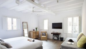Quarto com cama, poltrona, televisão e escrivaninha.