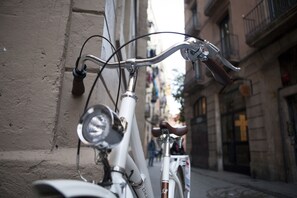 Uma bicicleta encostada a um edifício, com uma rua estreita ao fundo.