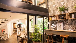 Um interior moderno com área de bar, banquetas de madeira, uma bicicleta e um vaso de planta.
