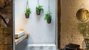 Um interior rústico com cachepots suspensos, uma estante de madeira e um espelho na parede.