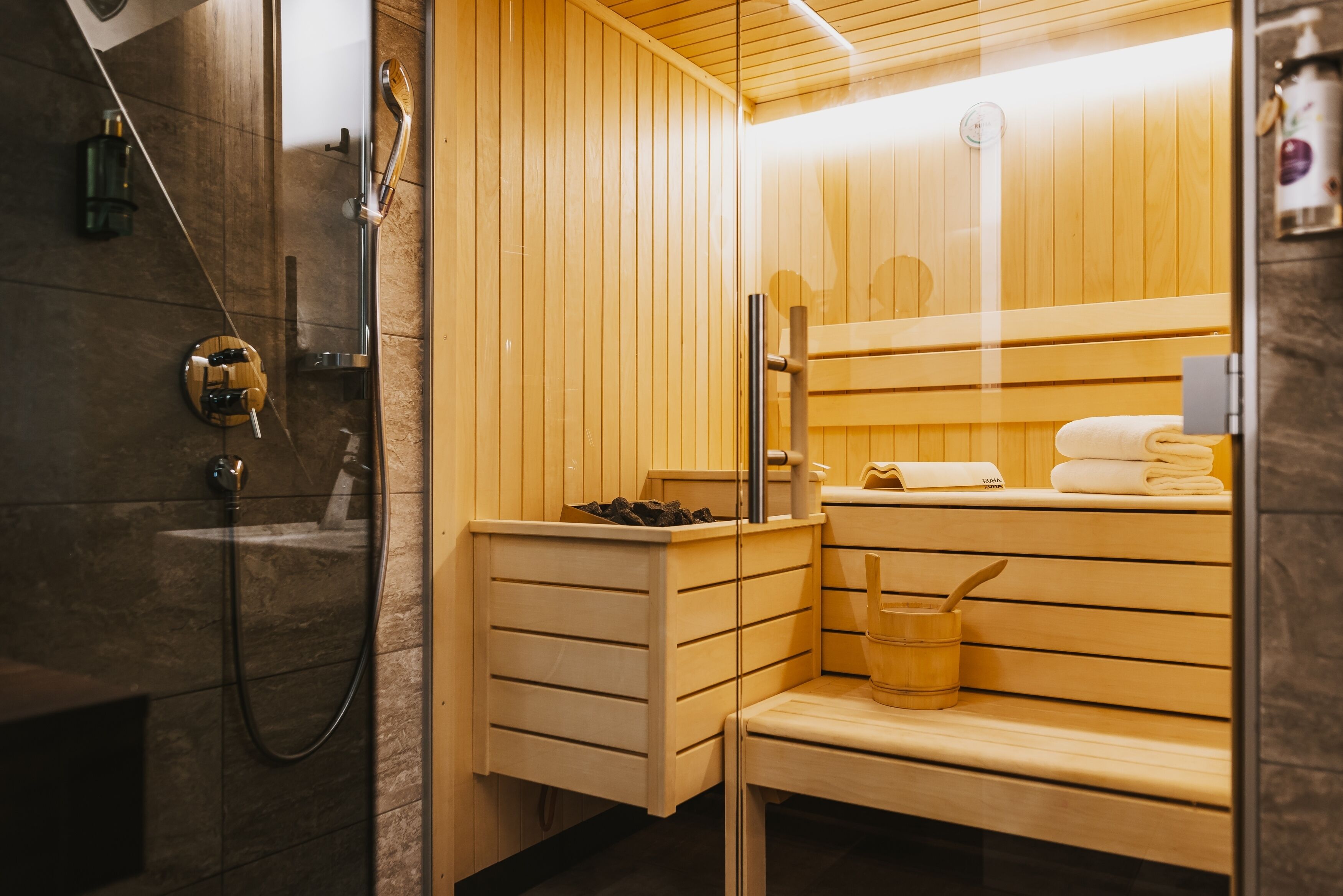 Uma sauna com bancos de madeira, porta de vidro e um porta-toalhas.